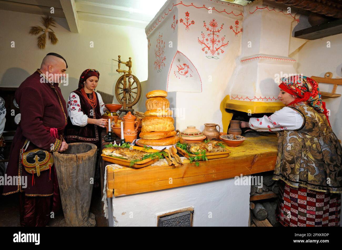 Woman in Ukrainian native dress using device "rogach" to cook ...