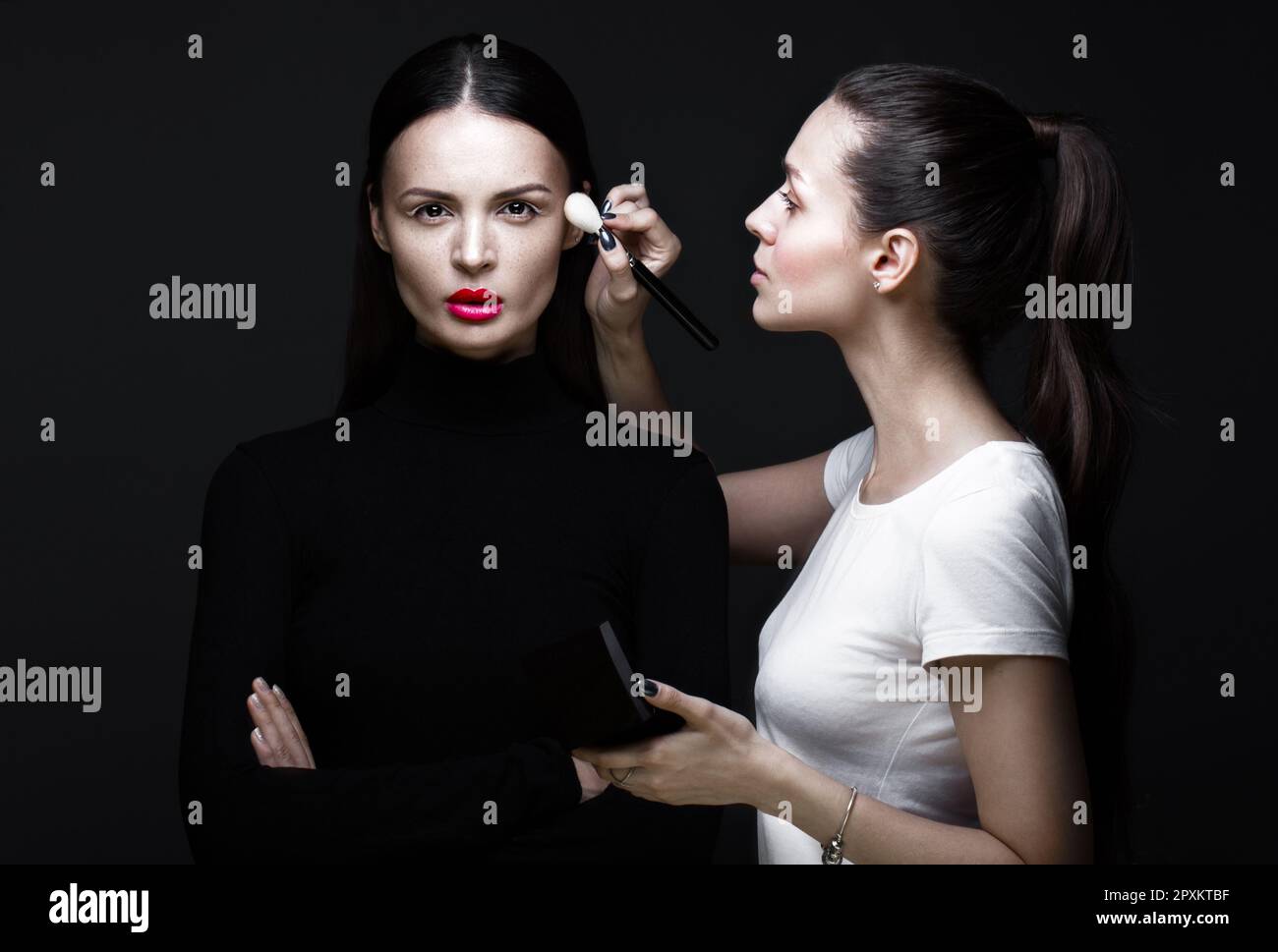 Two beautiful girls on a photo shoot to apply makeup to the face ...