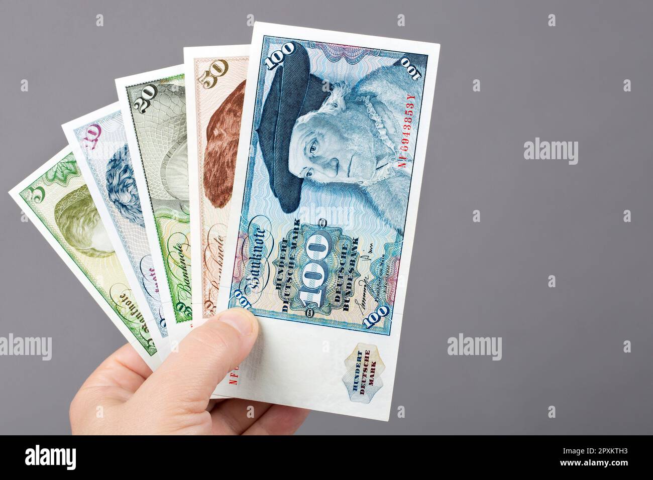 Deutsche money - Mark in the hand on a gray background Stock Photo - Alamy