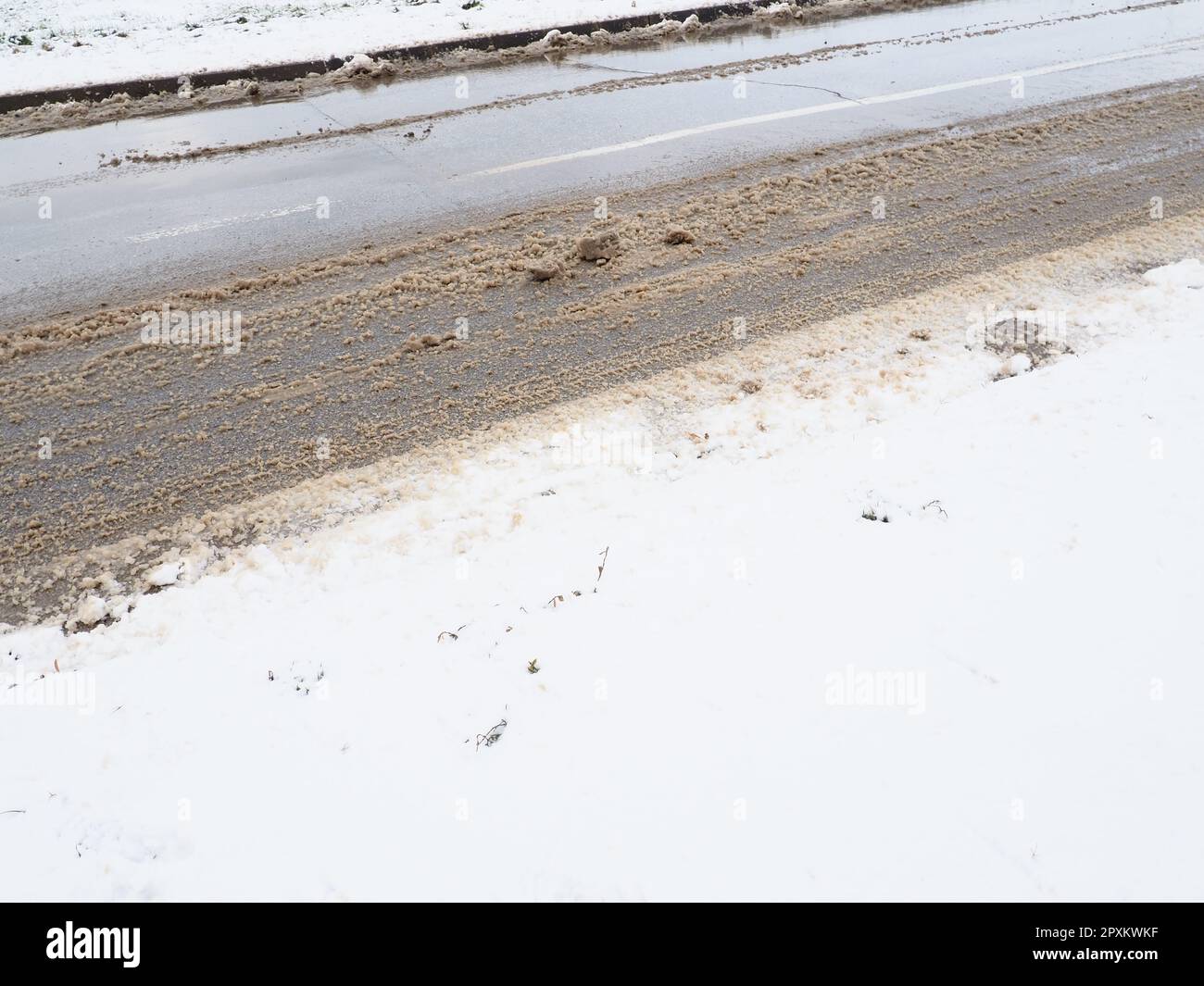 Roadside with a snowdrift. Difficult driving conditions. Wet slippery ...