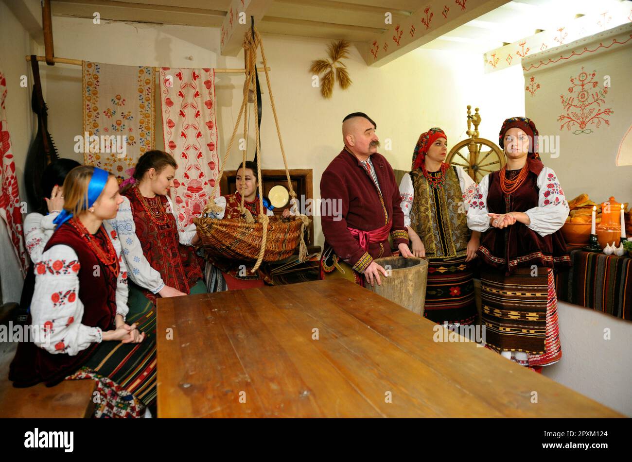 Family in Ukrainian native costumes gathered behind table to prepare ...