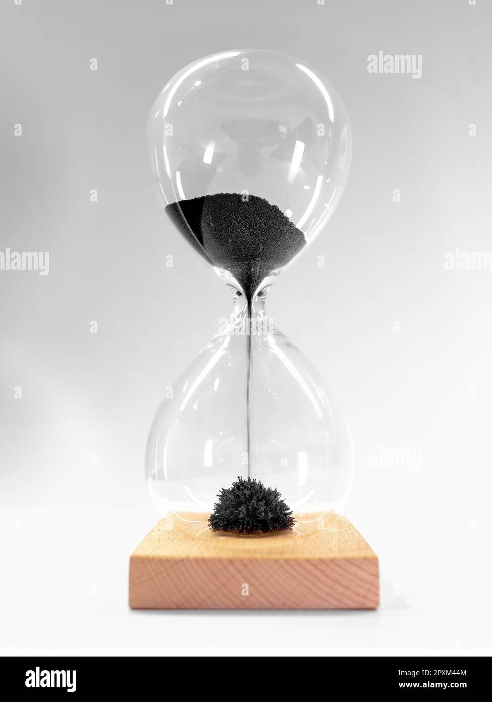A vertical of an hourglass with sand cascading through it on a white ...