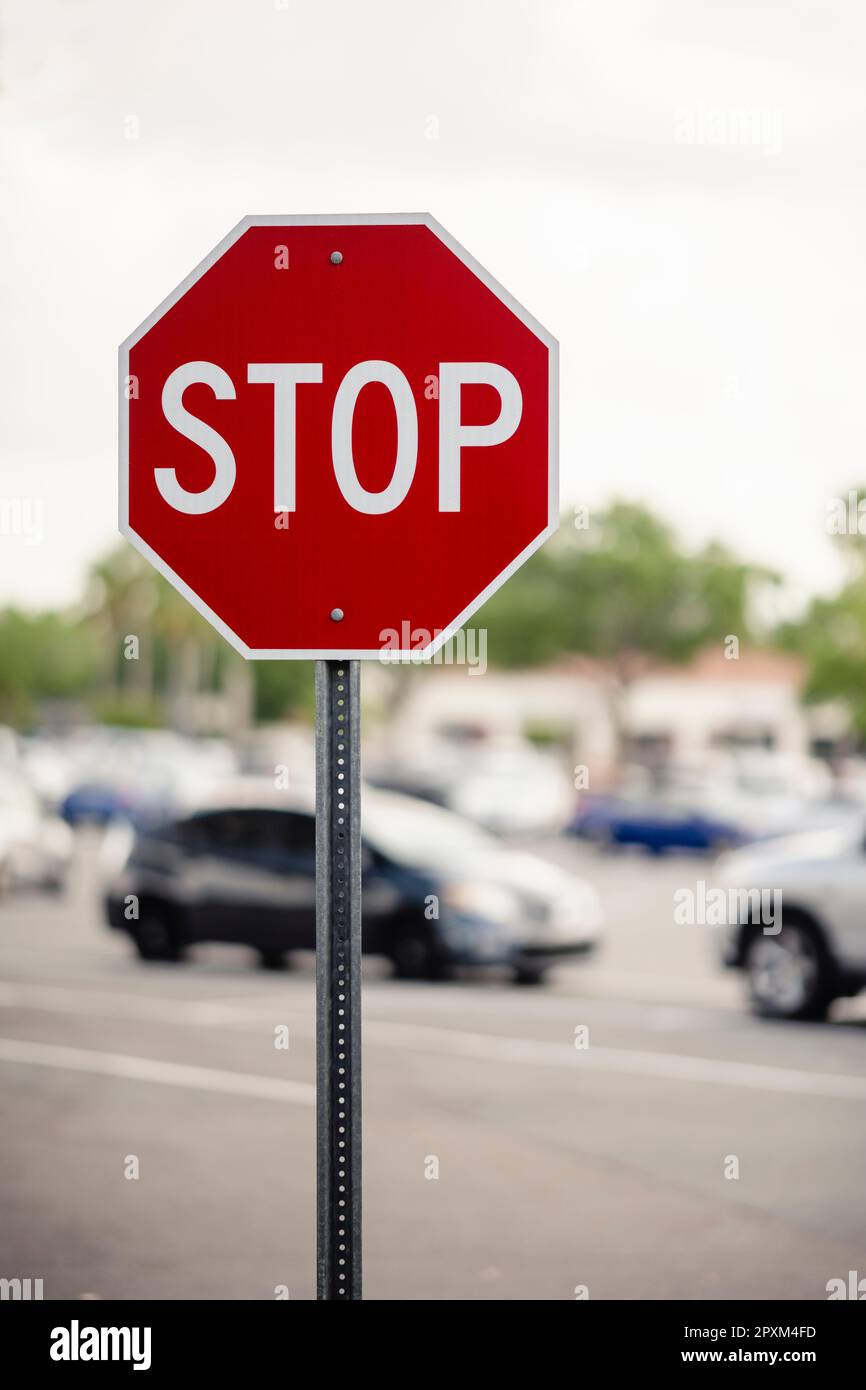An octagonal red and white stop sign in the foreground of a busy ...