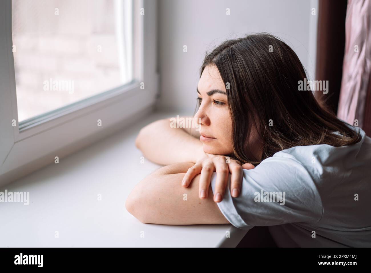 Lady lay down on the windowsill and looks out the window Stock Photo ...