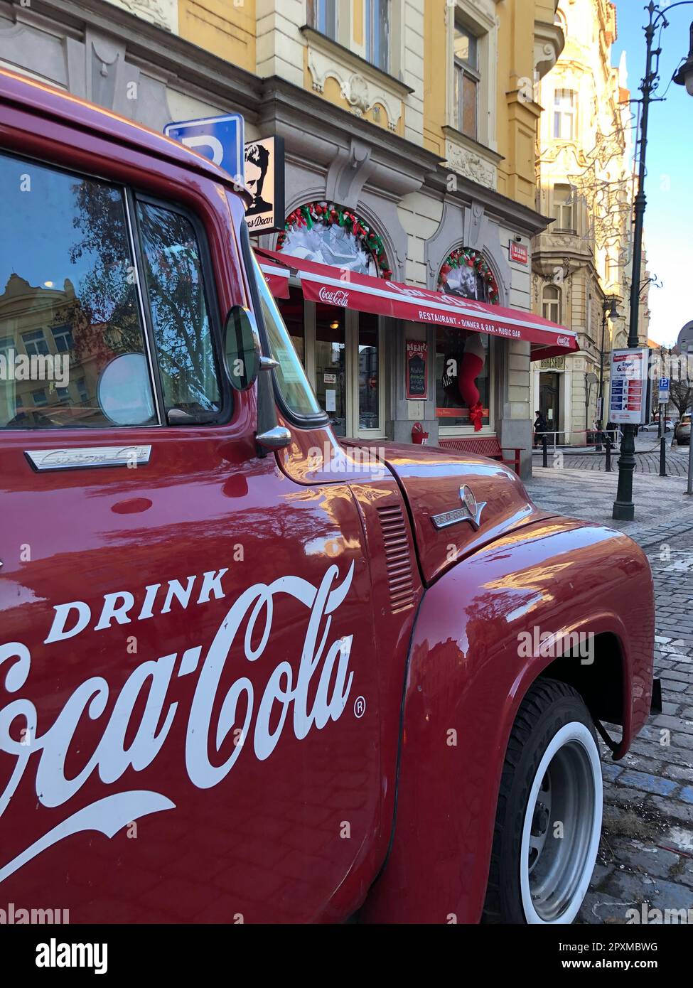 A vertical shot of a red coca cola car parked on the street in Europe ...