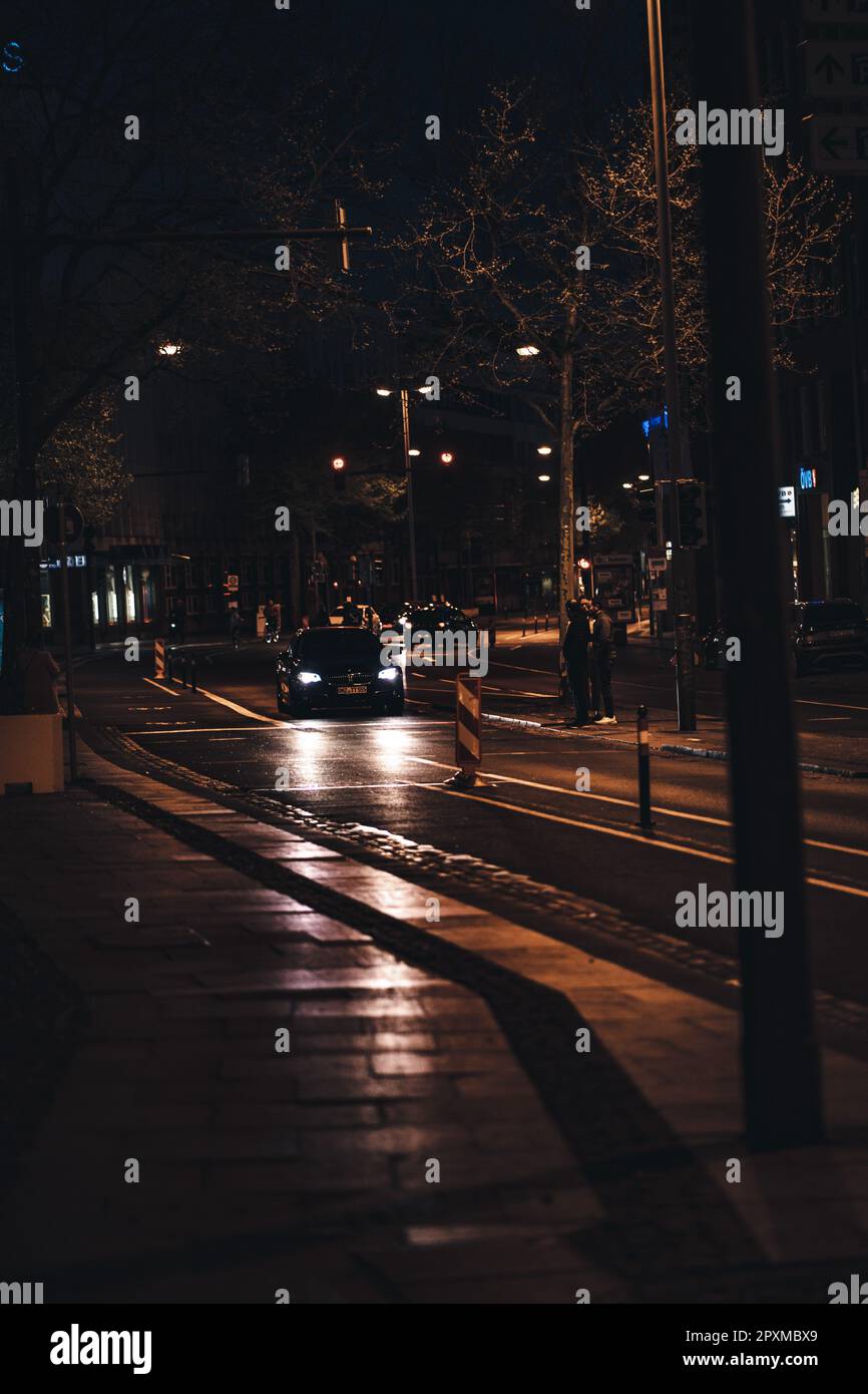A beautiful urban nightscape with a car driving along the street, its ...