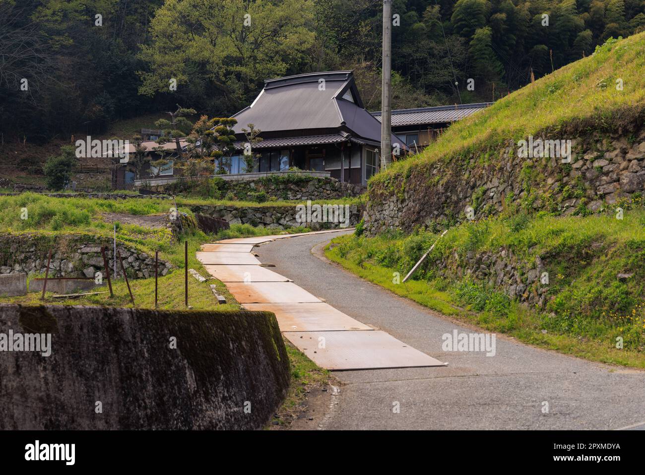 Narrow road by ancient stone wall to traditional Japanese house in ...