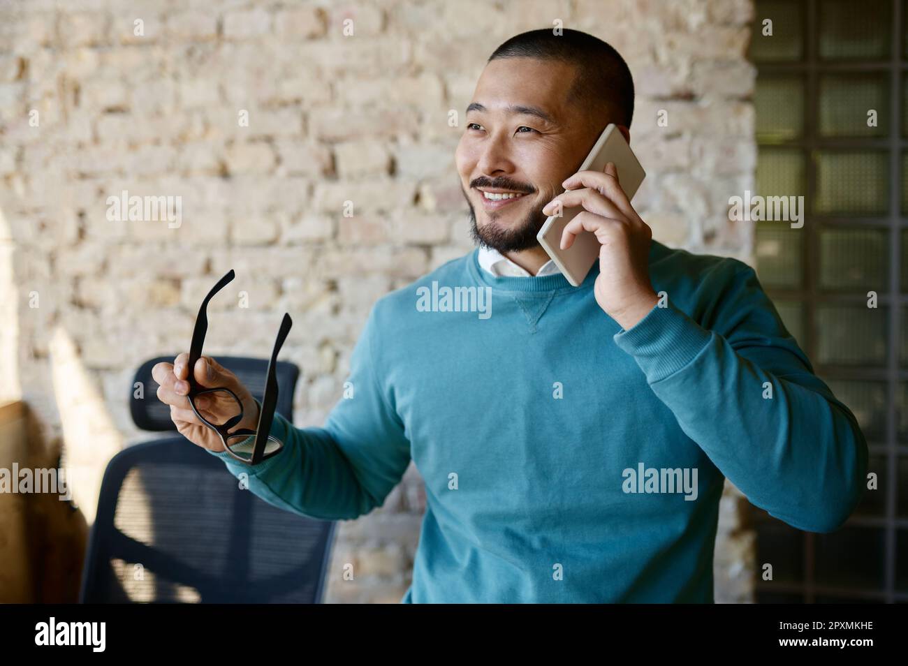 Young businessman talking mobile phone with client in office at ...