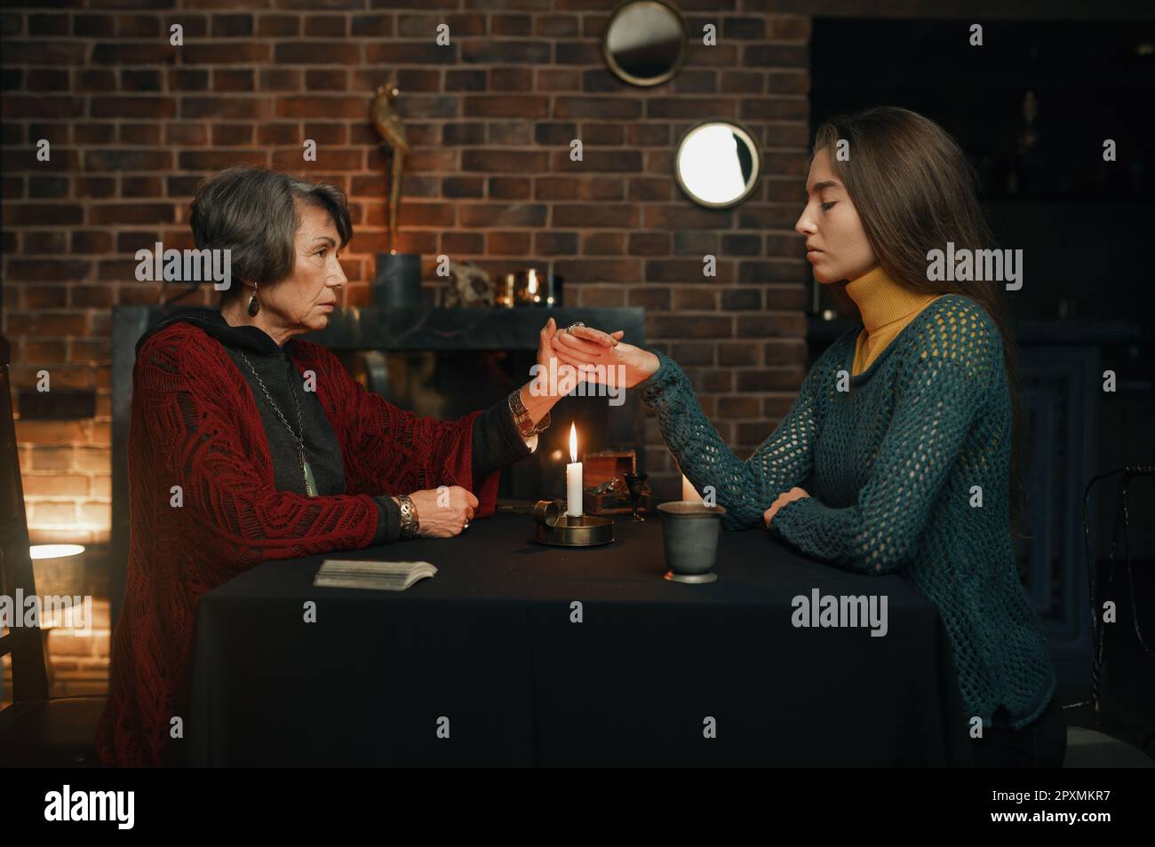 Fortune teller woman using burning candle flame for witchcraft spell ...