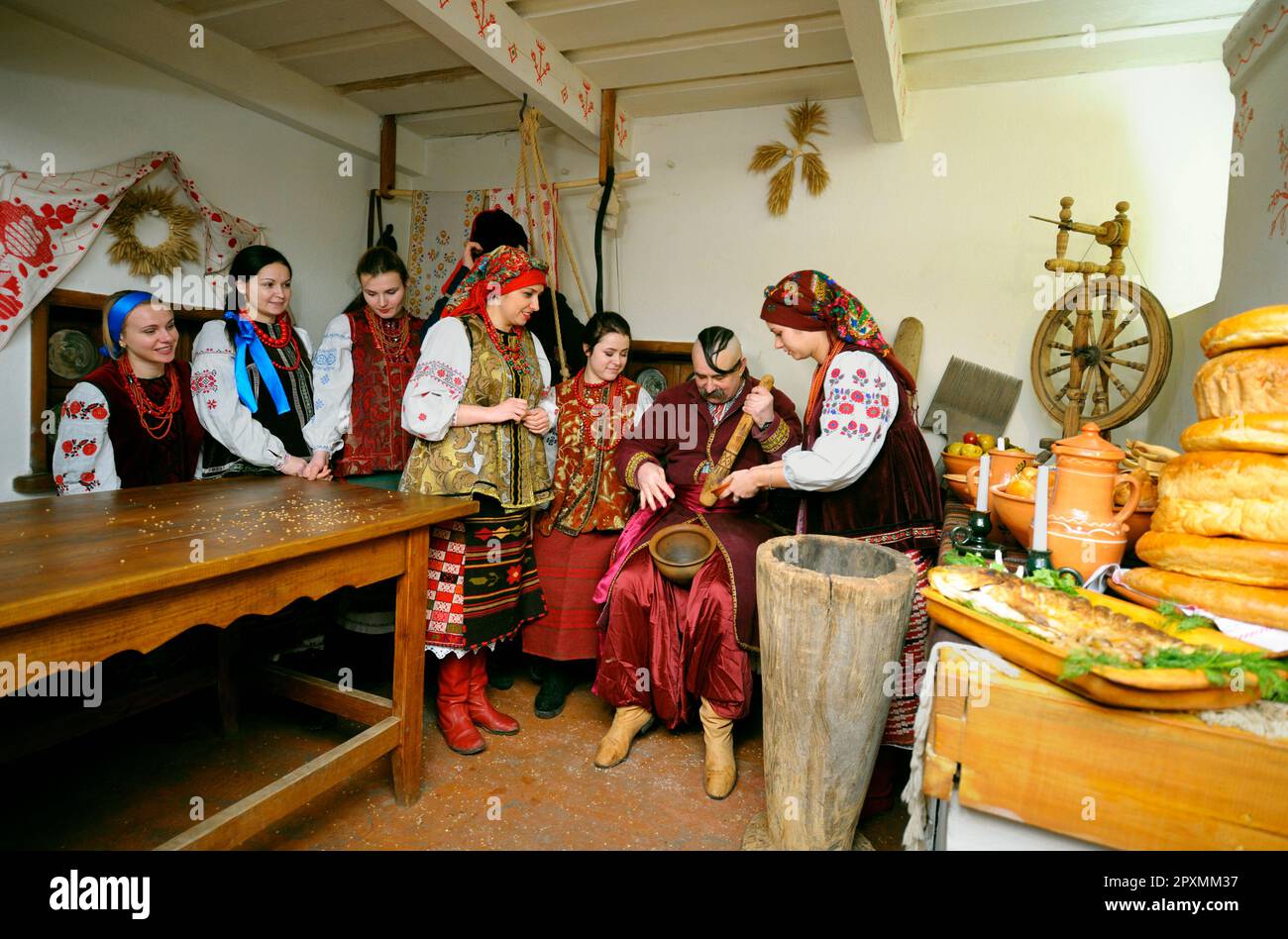 Family in Ukrainian native costumes gathered to cook traditional dish ...