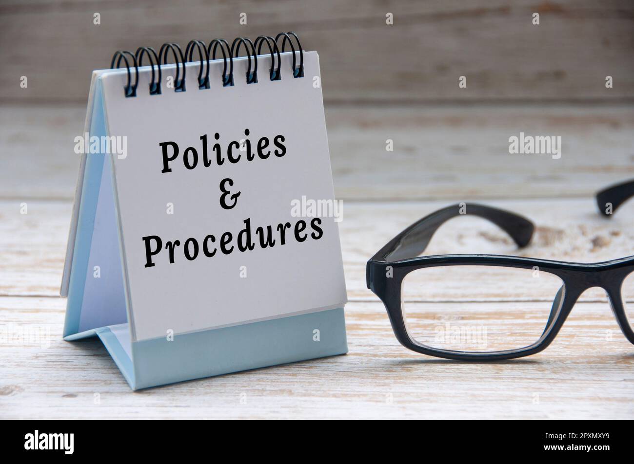 Policies and procedures text on notepad with glasses on white wooden ...