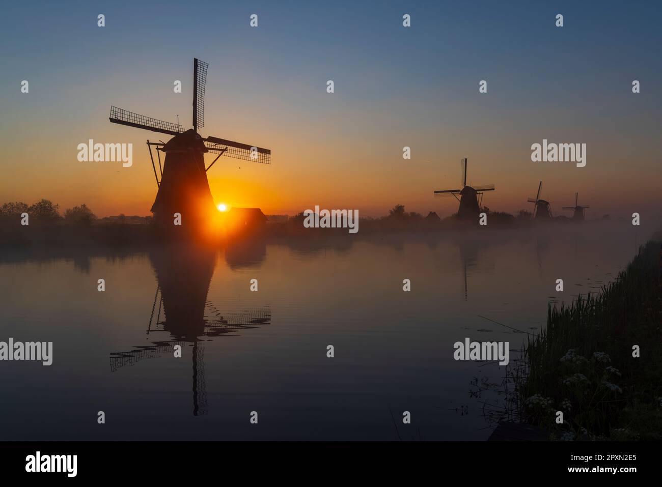 Traditional Dutch windmills with a colourful sky just before sunrise in ...