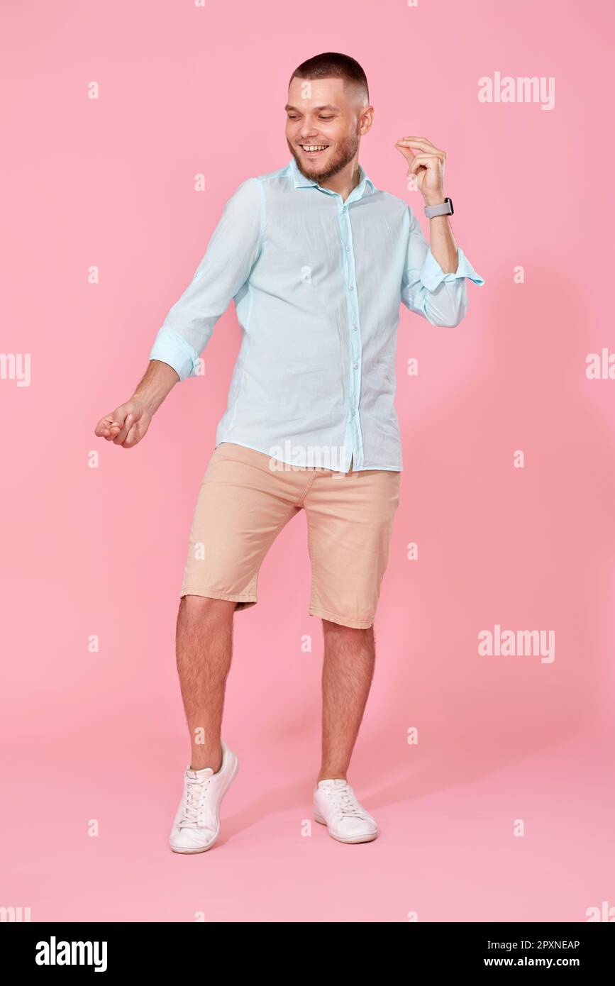 cheerful young happy man dance on pink background. vacation summer ...