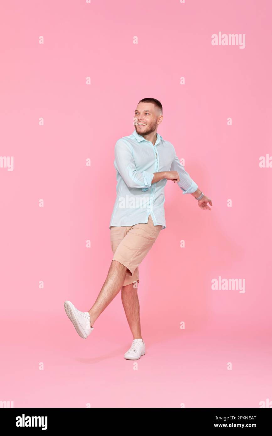 cheerful young happy man dance on pink background. vacation summer ...