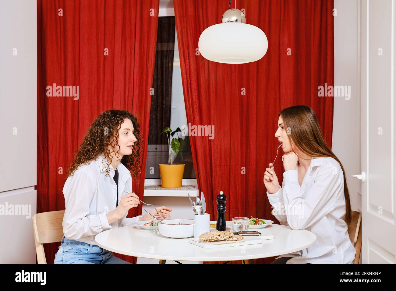 Two women having meal together at home and talking Stock Photo - Alamy