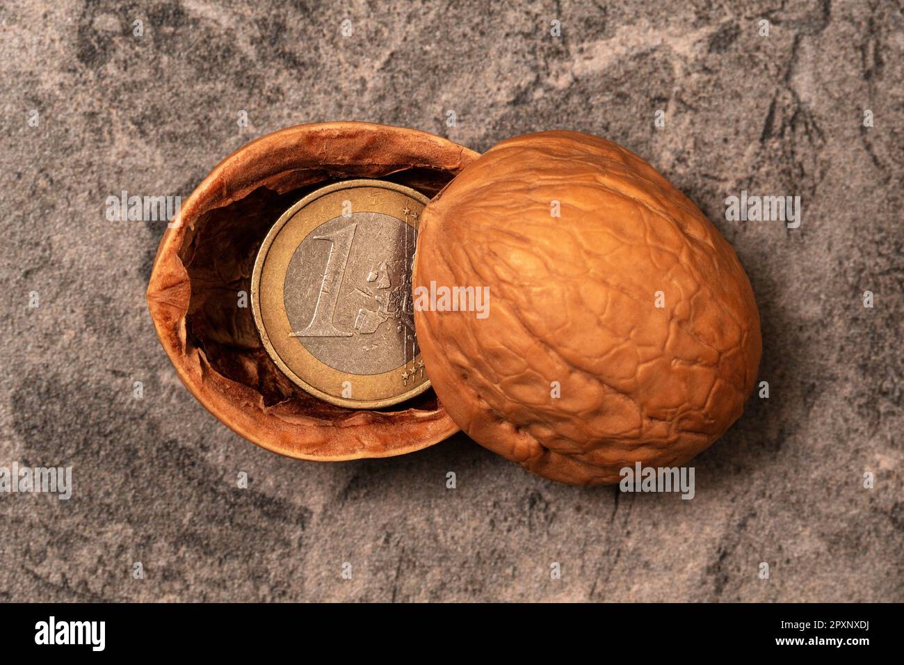 One Euro coin in a cracked walnut shell. Financial success Stock Photo ...