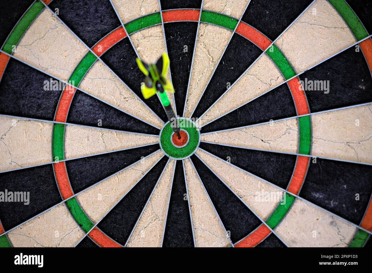 Single black and green dart stuck in the bullseye of a dartboard. Close ...