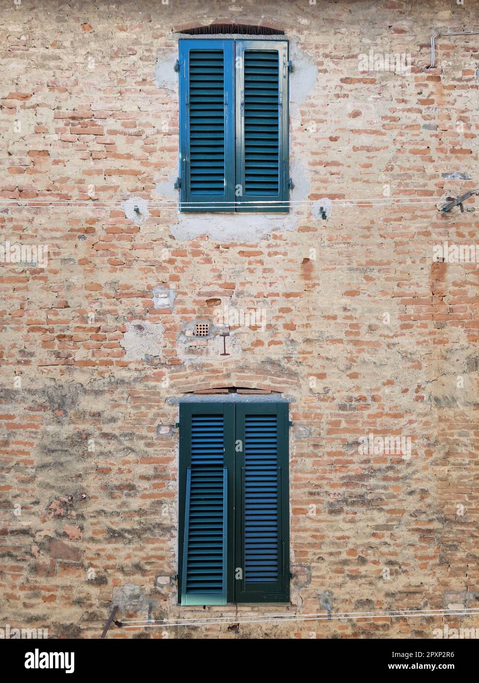 A close-up view of a vintage building featuring a set of green shutters ...