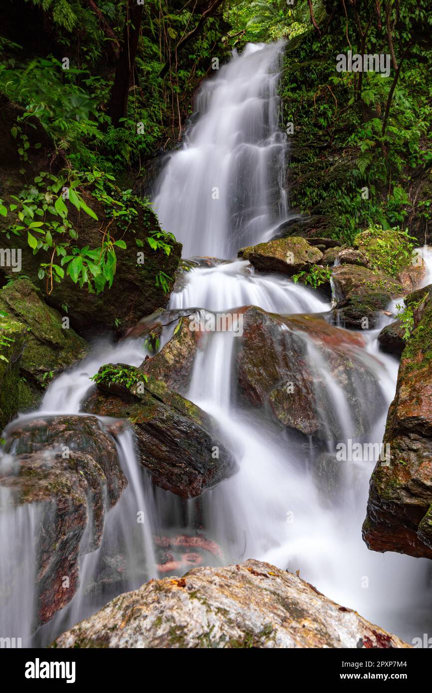 A beautiful waterfall cascading over rocks in a lush jungle setting ...