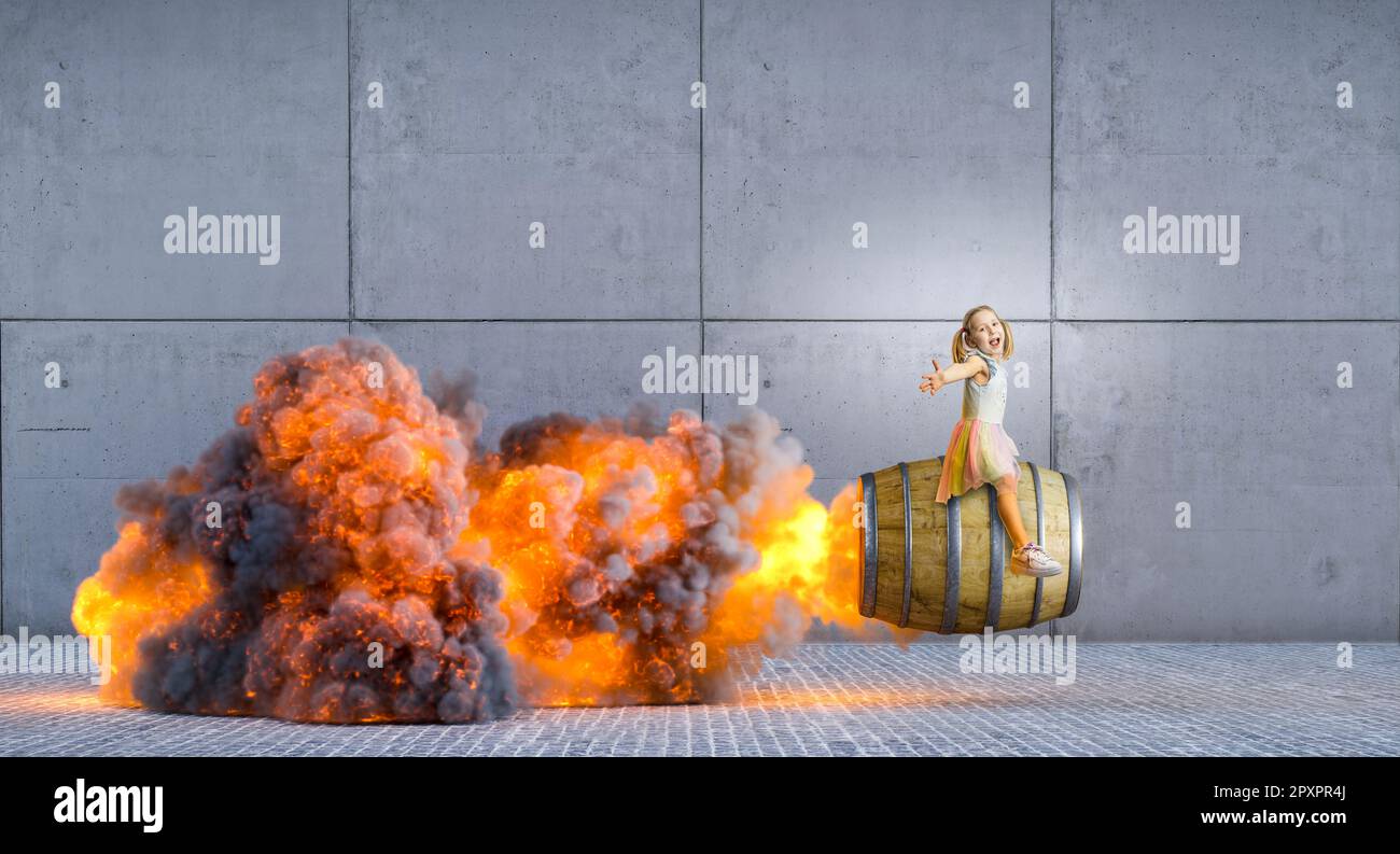 Happy little girl rides a large wooden barrel with propulsion, flames ...