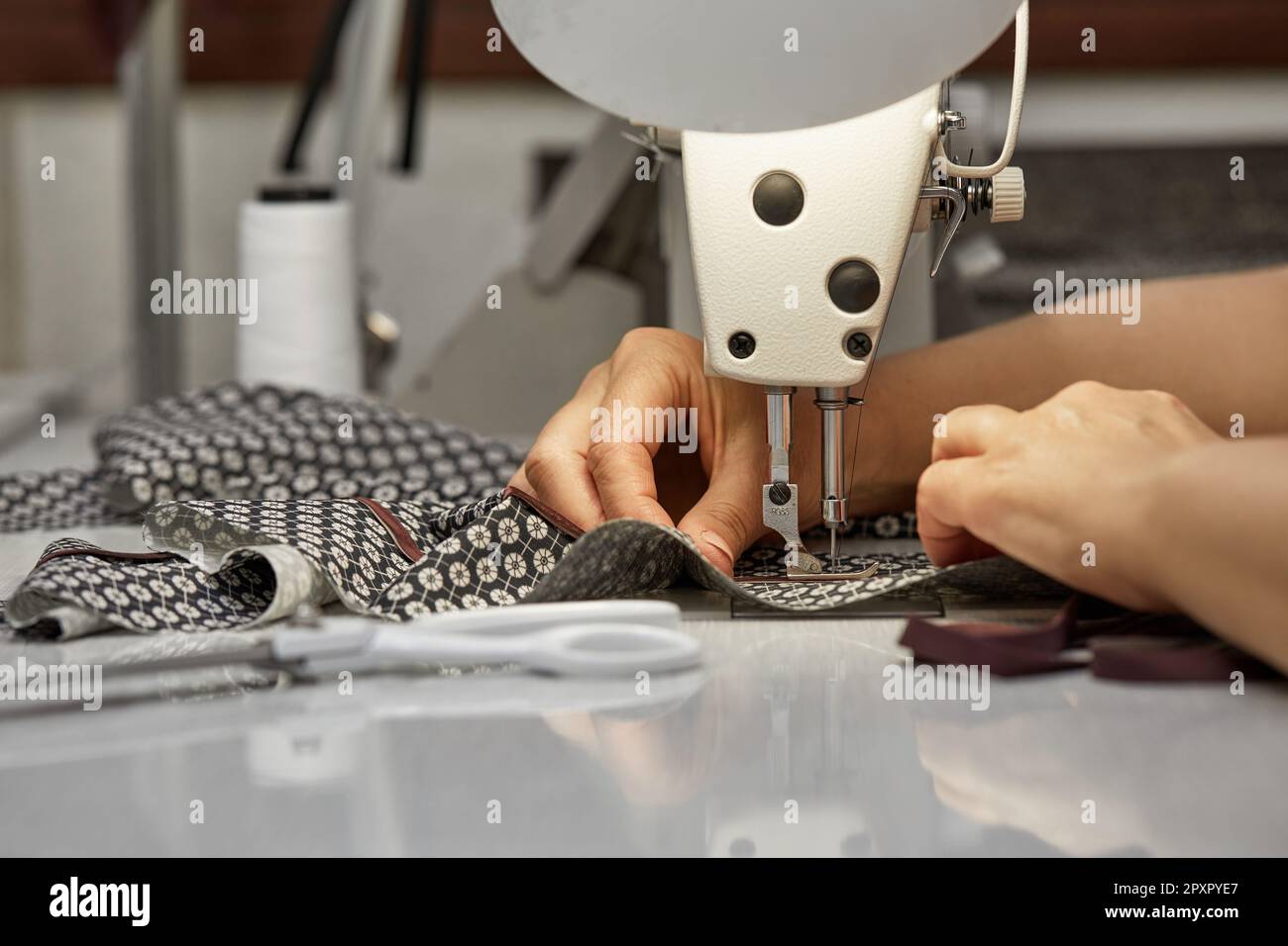girl seamstress sew on the sewing machine. Women's hands sewing on the sewing machine. Tailoring ...