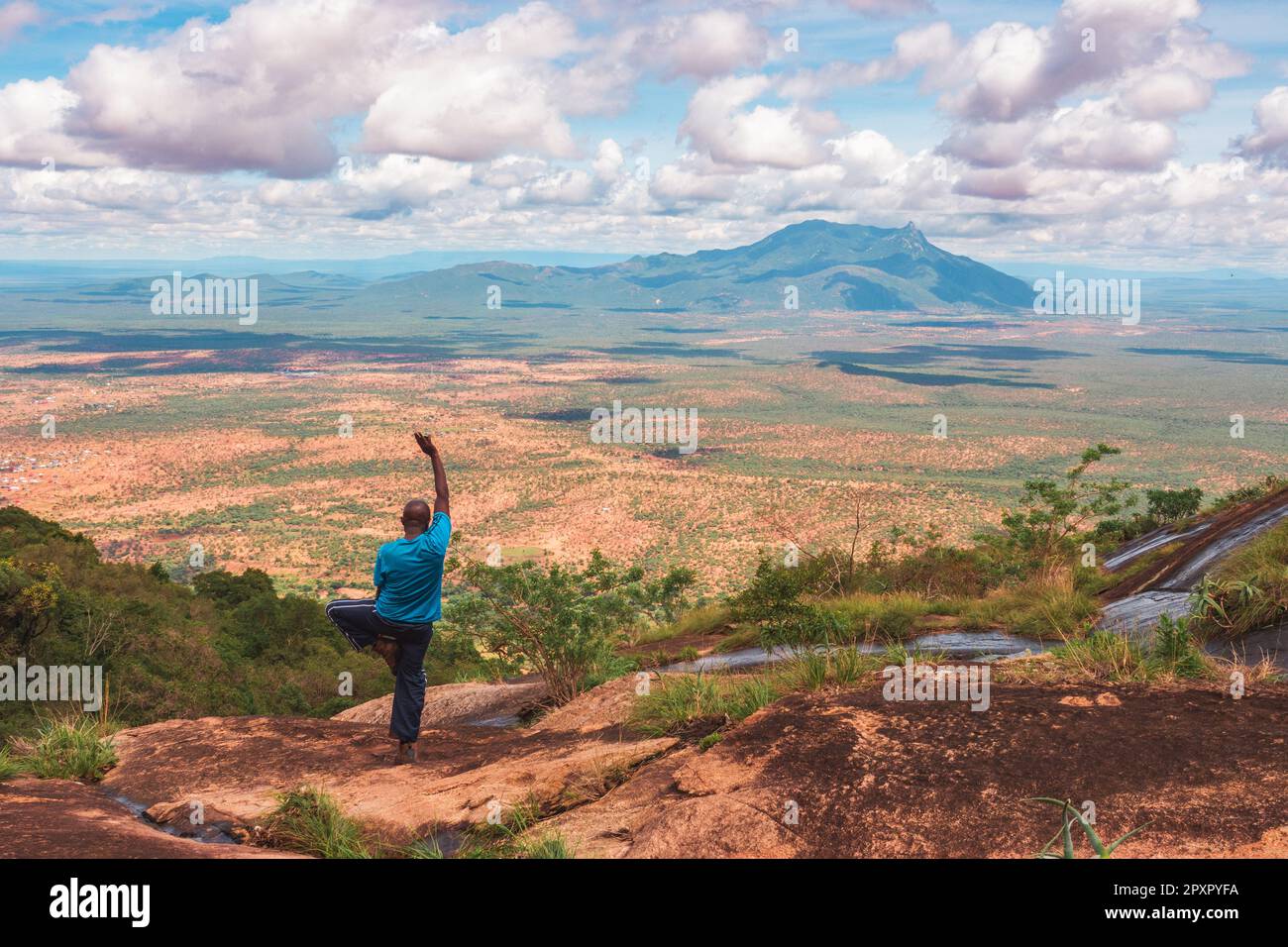 Rear view of a hiker doing a yoga pose against the background of Mount ...