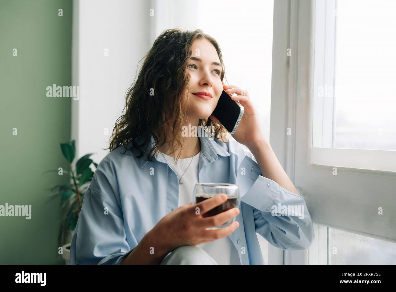 Cheerful young woman in casual attire chatting and flirting with her ...