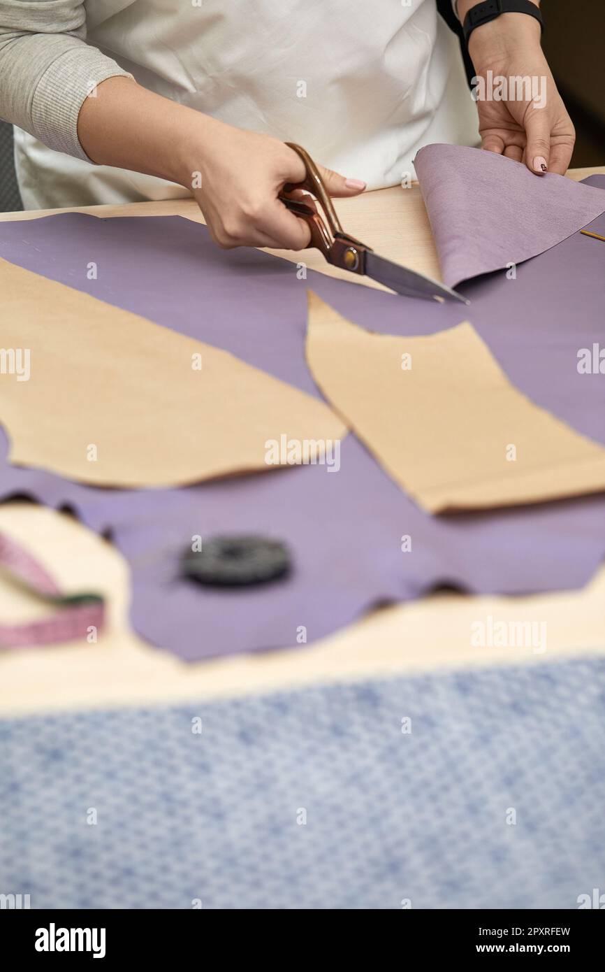 Workplace of seamstress. Dressmaker cuts textile on the sketch lines ...
