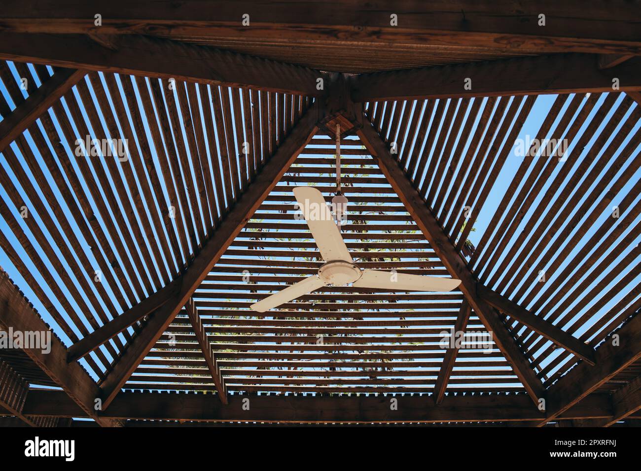 White dirty outdoor ceiling fan on wooden roof. Old vintage cooling and ...