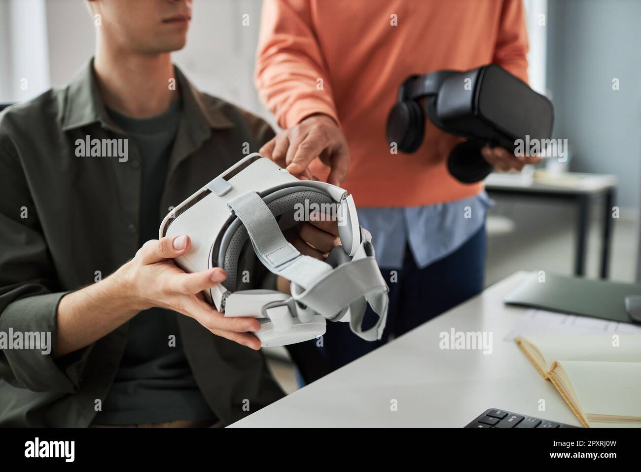 Close-up of young developers testing VR glasses and discussing computer ...
