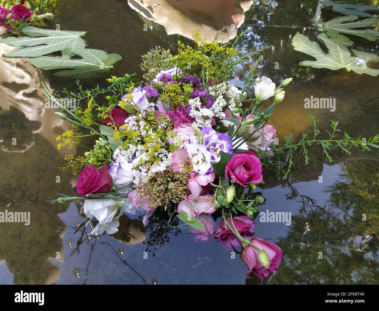 pink and red roses in a bouquet floating in the water of a fountain ...