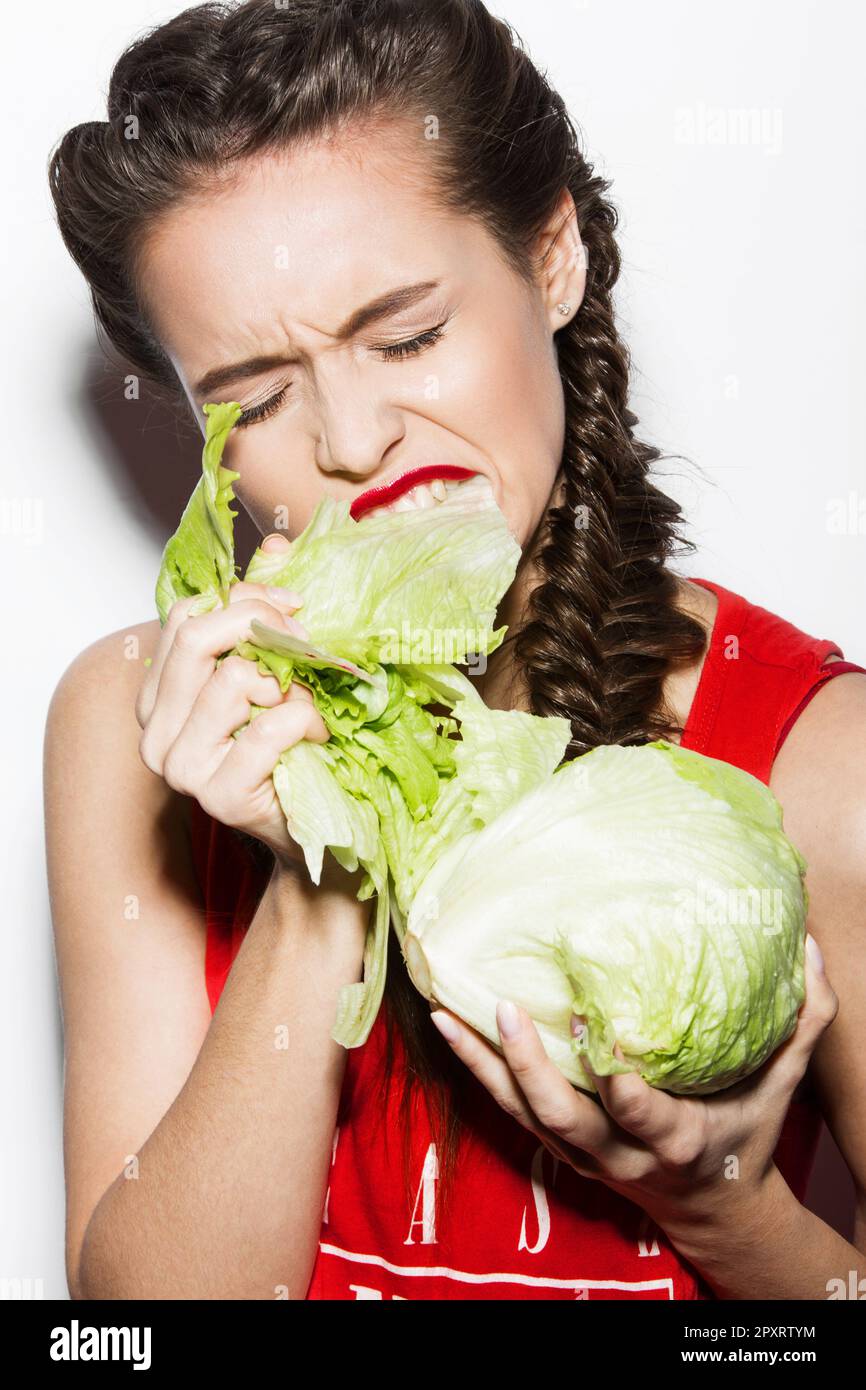 Daring funny girl with braids and red lips, emotional eating cabbage ...