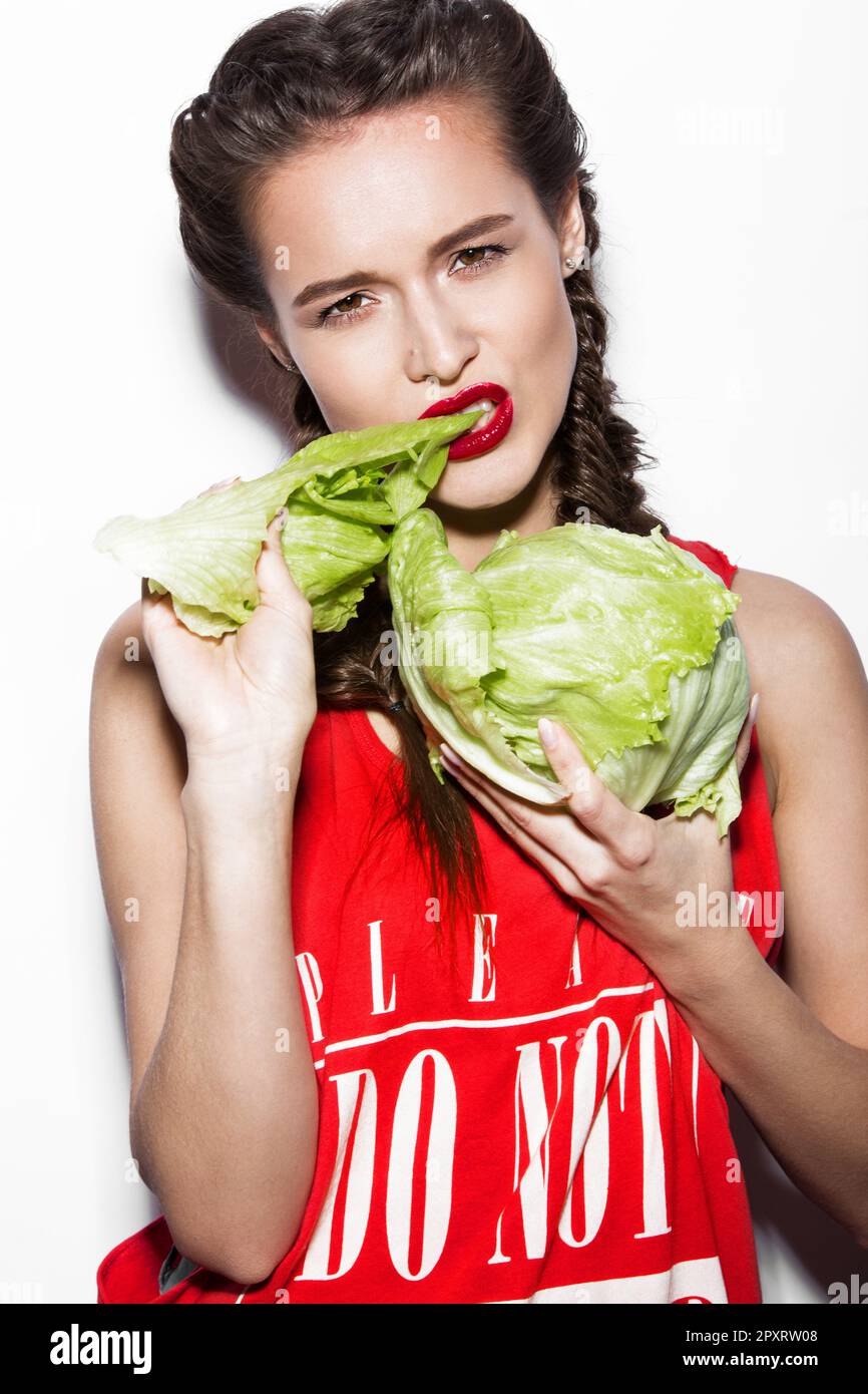 Daring funny girl with braids and red lips, emotional eating cabbage ...