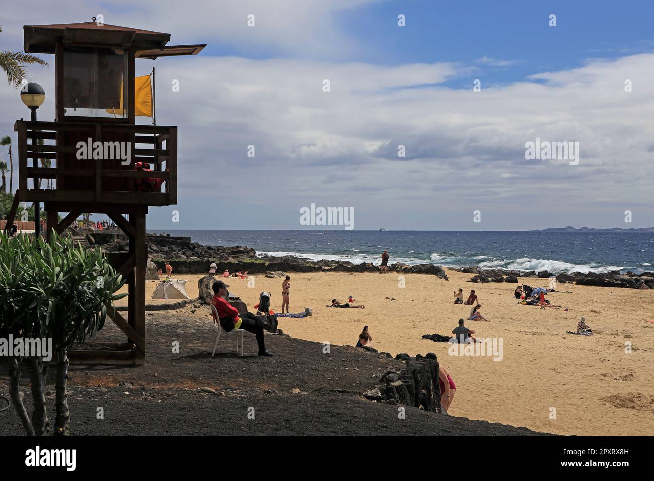 Lifeguard station wooden tower, with life guard sitting on a chair on ...