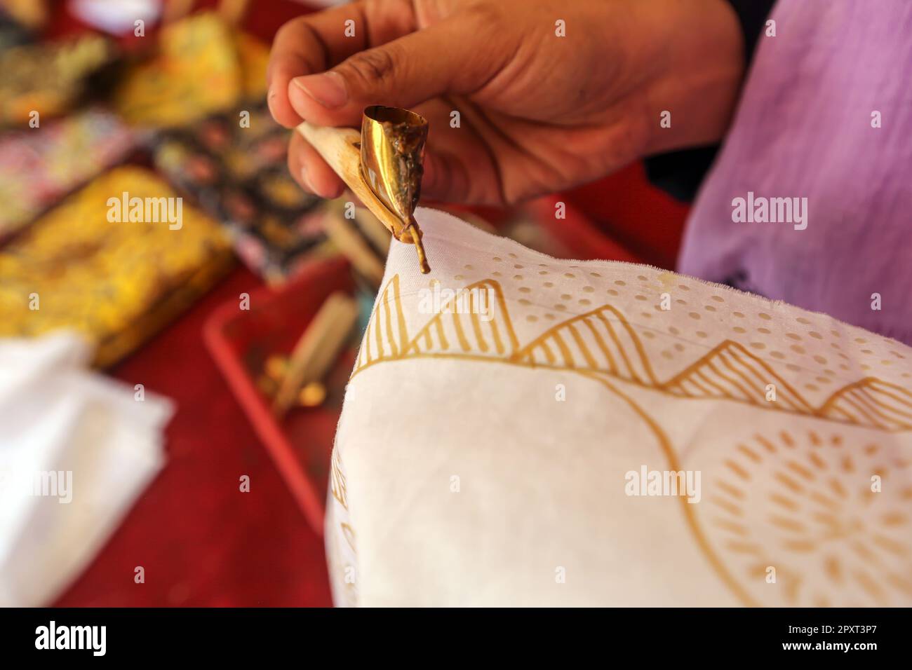 hand painting batik on a white cloth with a batik canting tool ...