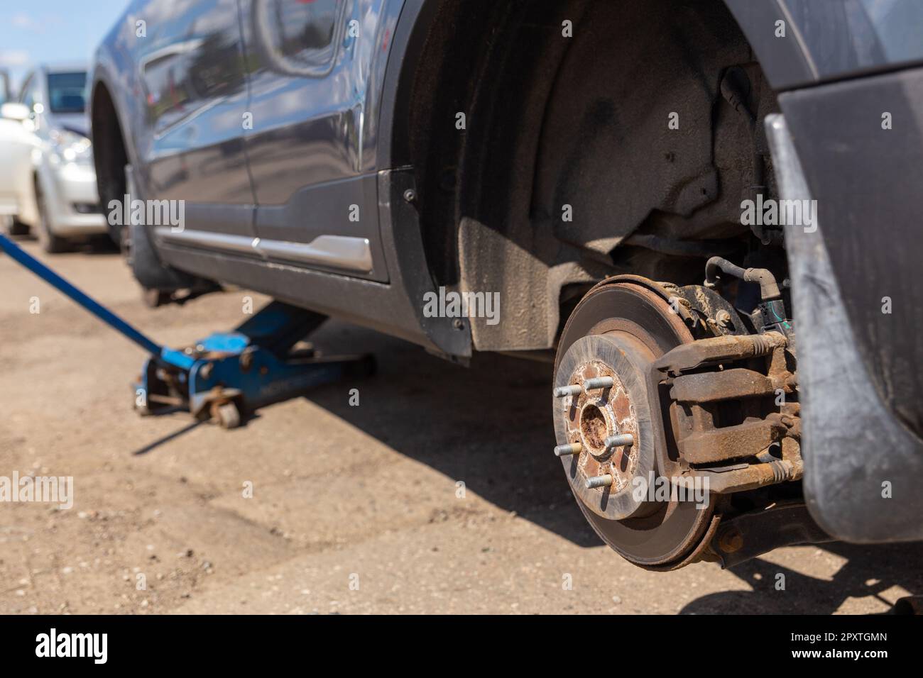 Car on tire mounting with removed wheel on pneumatic jack, seasonal ...