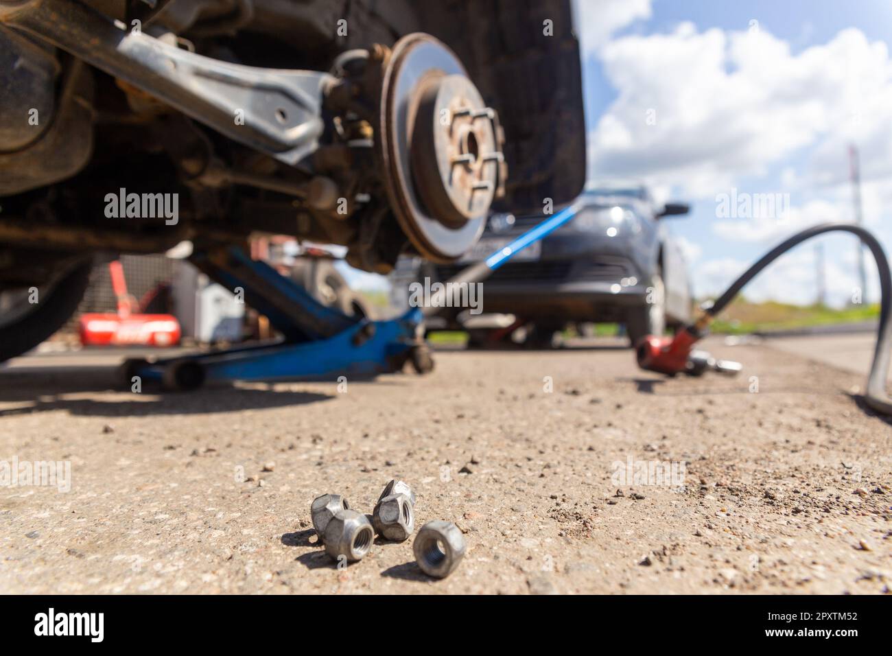 Car on tire mounting with removed wheel on pneumatic jack, seasonal ...