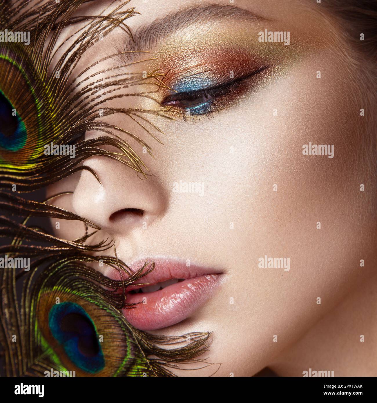 Beautiful girl with bright colored makeup and peacock feather on her ...