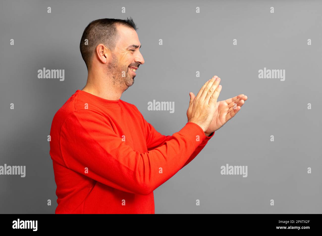 Bearded hispanic man in profile wearing a red jumper feeling happy ...