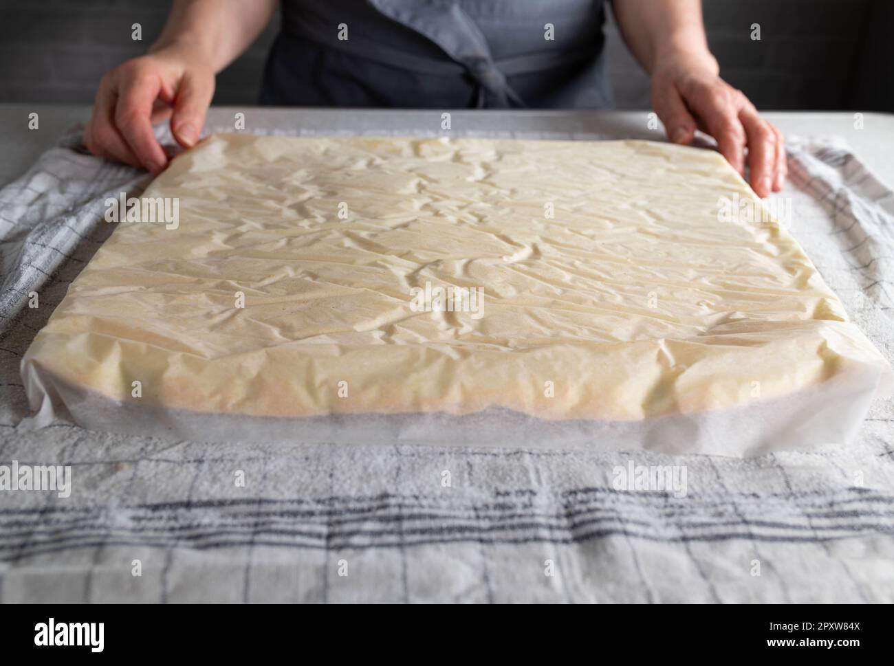 Sponge cake base upside down for removing baking paper on kitchen table ...