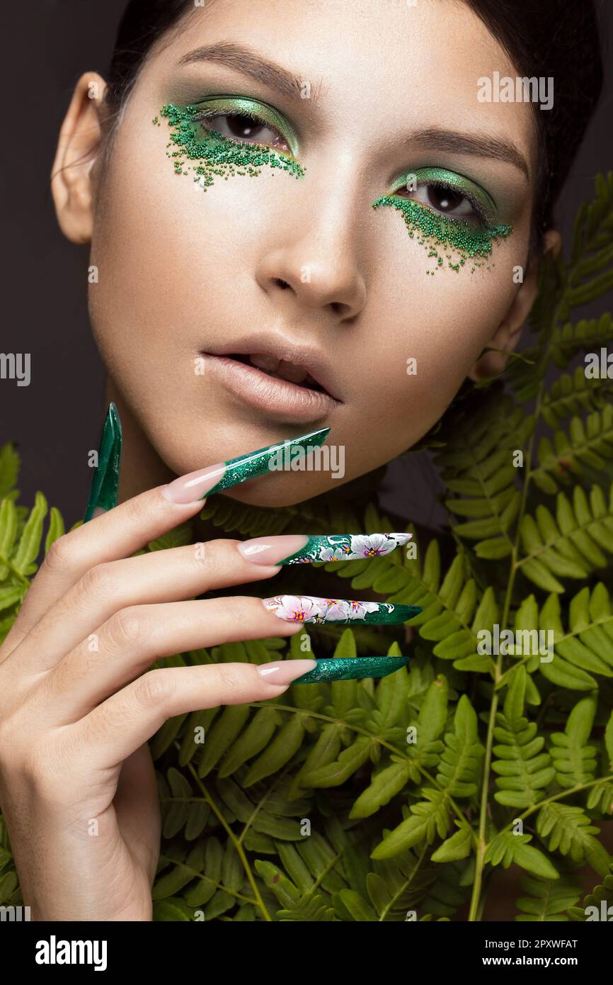 Beautiful girl with art make-up, fern leaves and long nails. Manicure ...