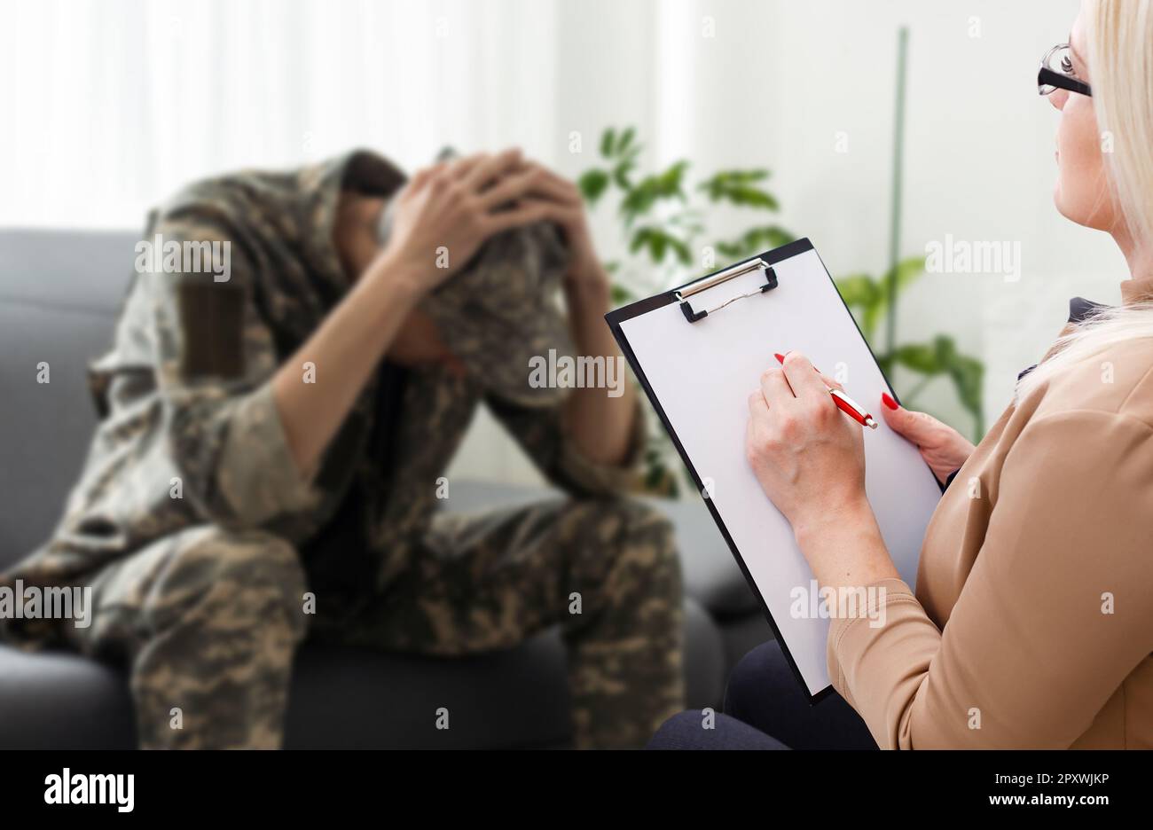 Psychologist making notes during therapy session with sad male soldier ...