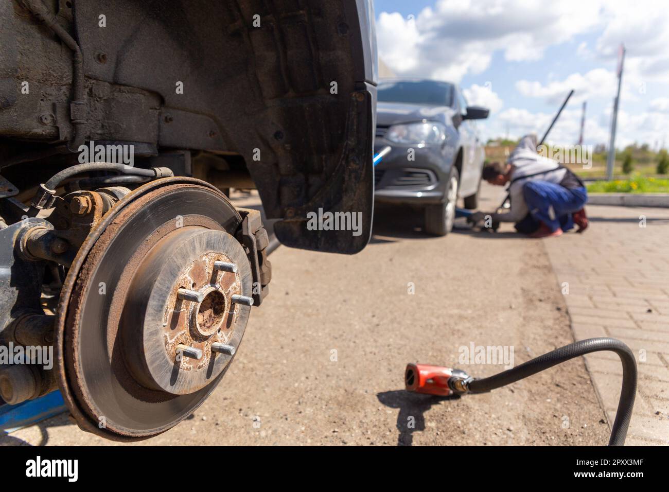 Car on tire mounting with removed wheel on pneumatic jack, seasonal ...