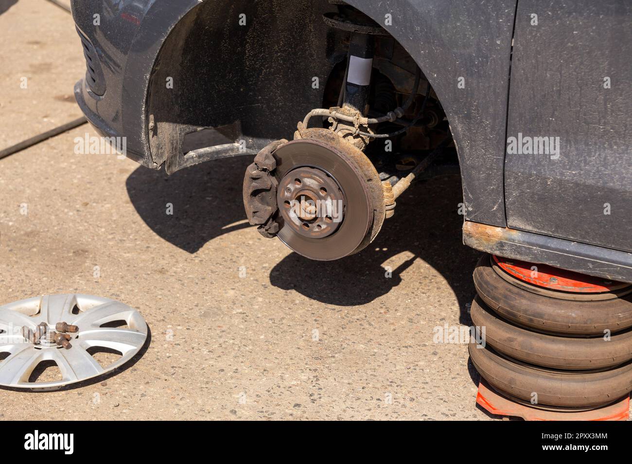 Car on tire mounting with removed wheel on pneumatic jack, seasonal ...