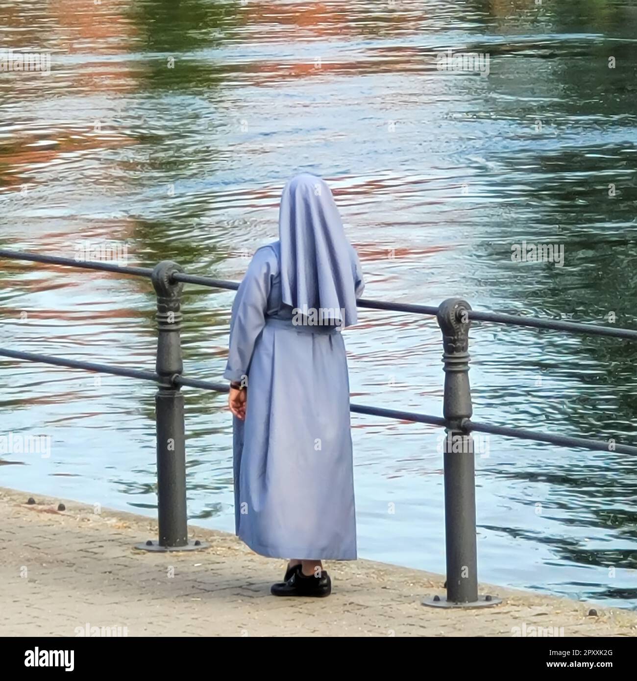 A nun stands by a river and looks at the water Stock Photo - Alamy