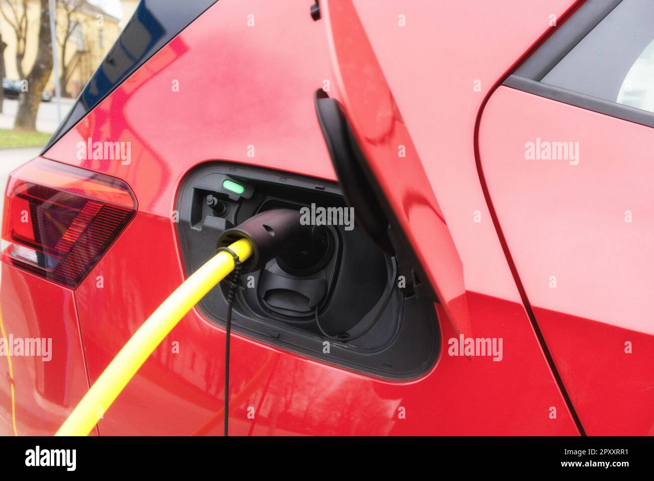 A red car with a black roof and a yellow electric cable stuck in it ...