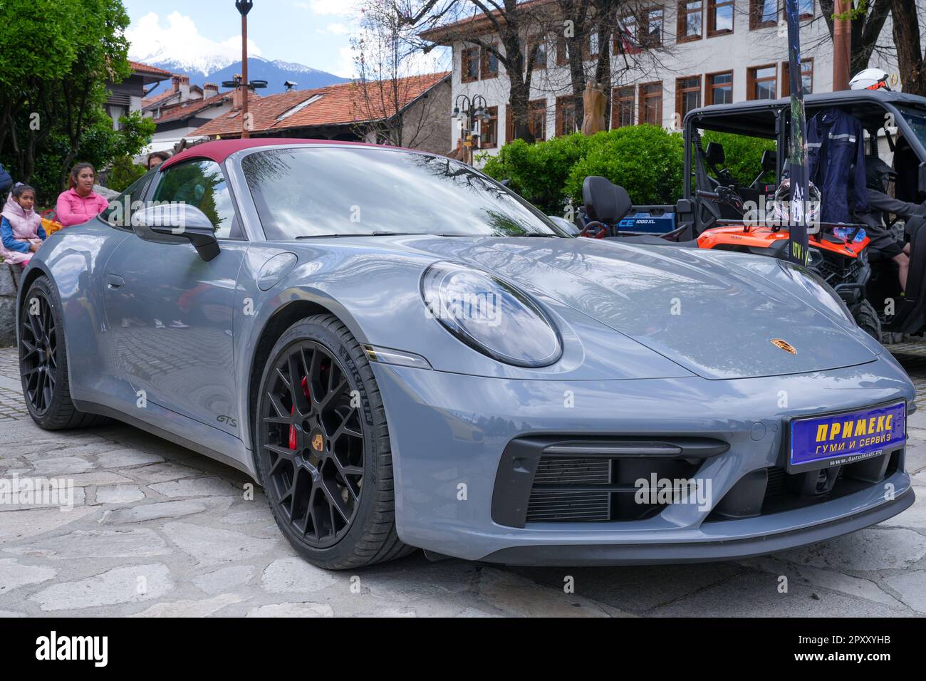 A Porsche GTS is shown parked in a urban environment alongside a modern ...