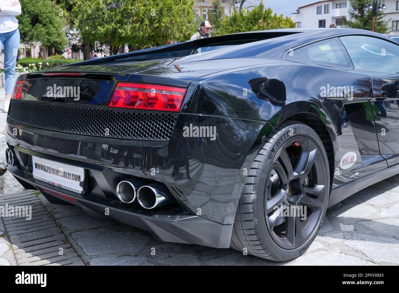 A man stands in front of a black Lamborghini , admiring the rear view ...