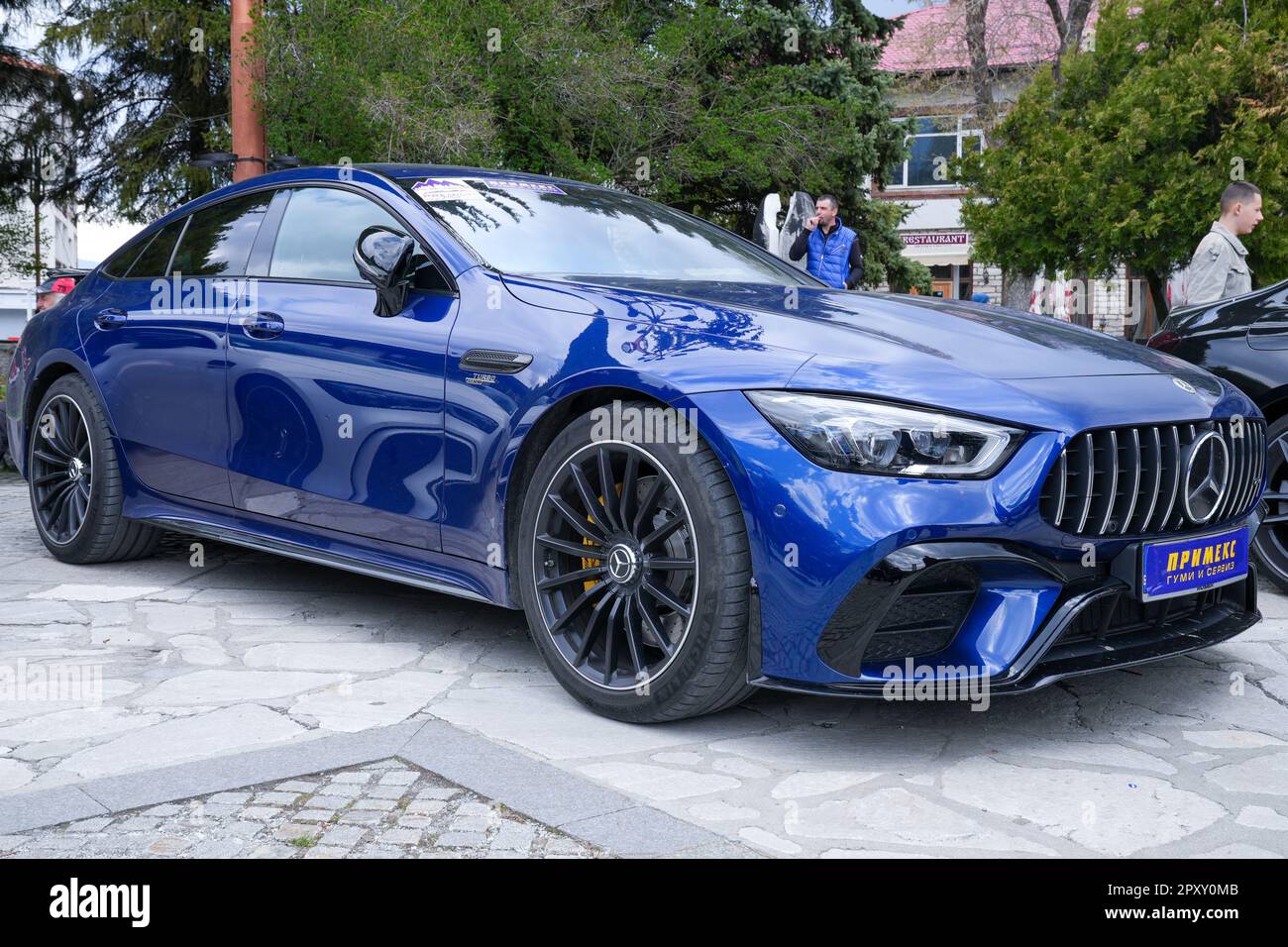 A sleek blue Mercedes Benz vehicle parked on a paved lot surrounded by ...
