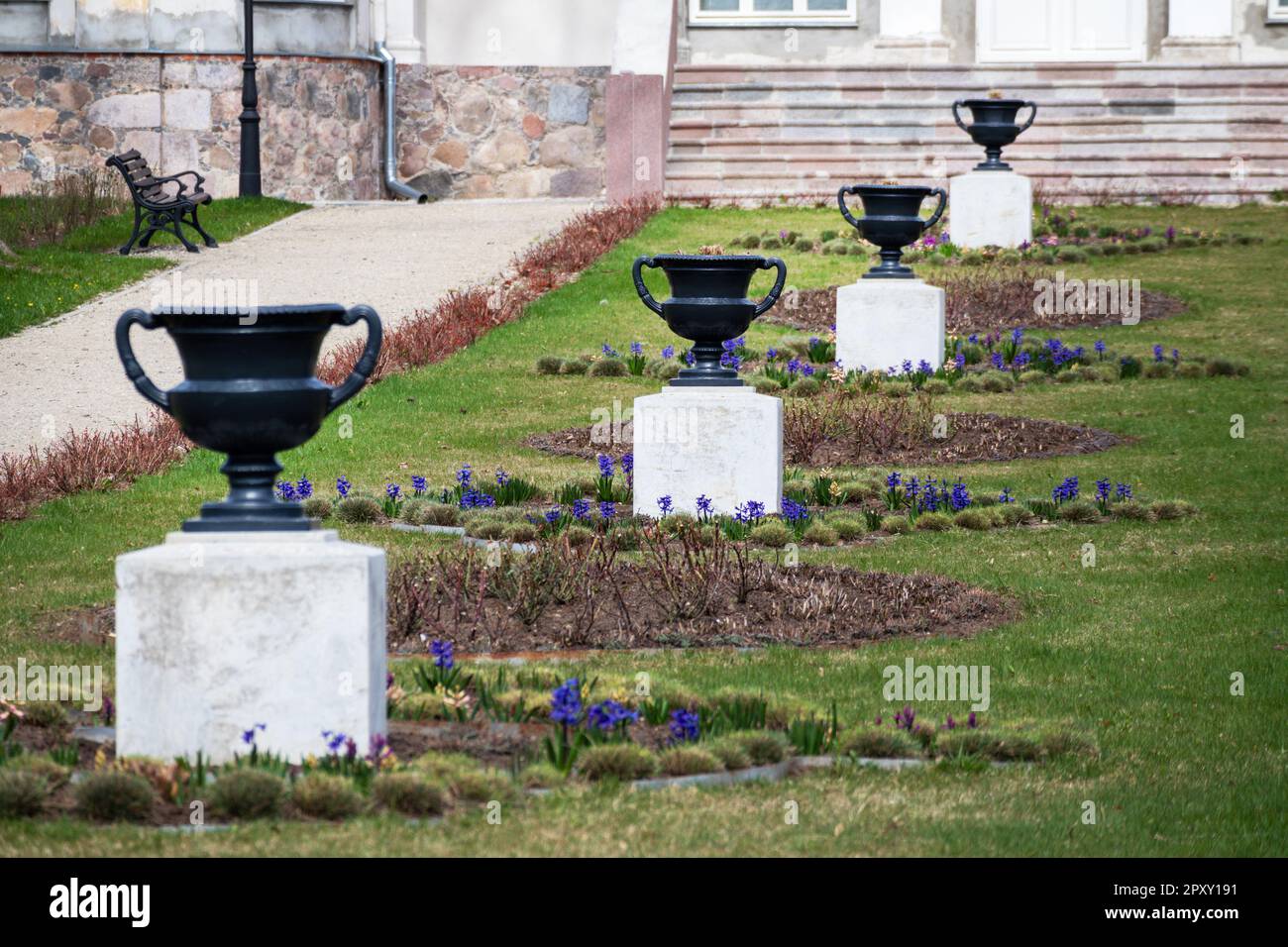 A row of Greek urns on white concrete pillars is displayed in front of ...